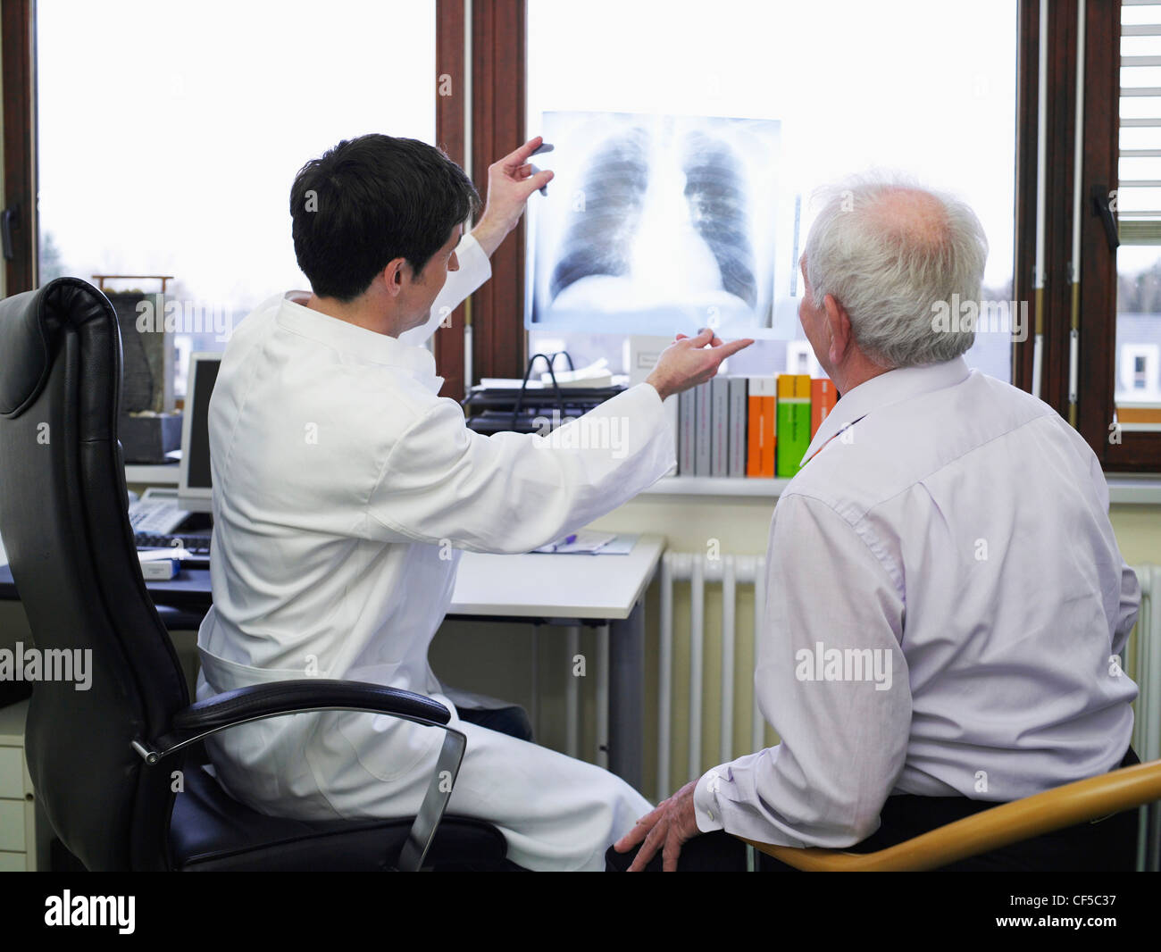 Germany, Hamburg, Doctor showing x-ray report to patient Stock Photo ...