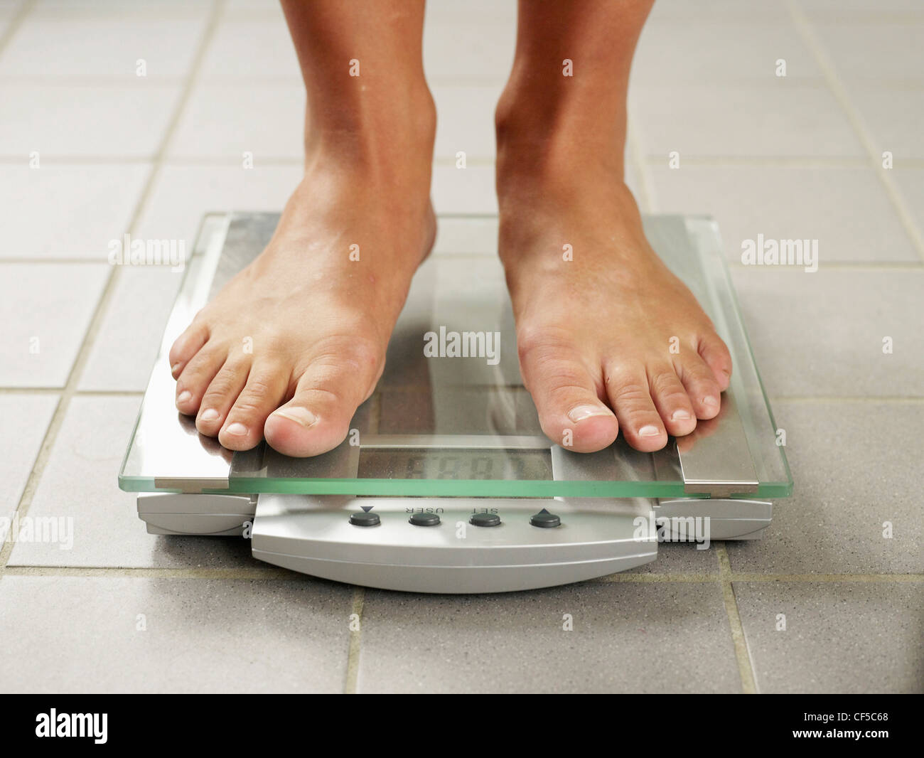 Mid adult woman standing on scales Stock Photo - Alamy
