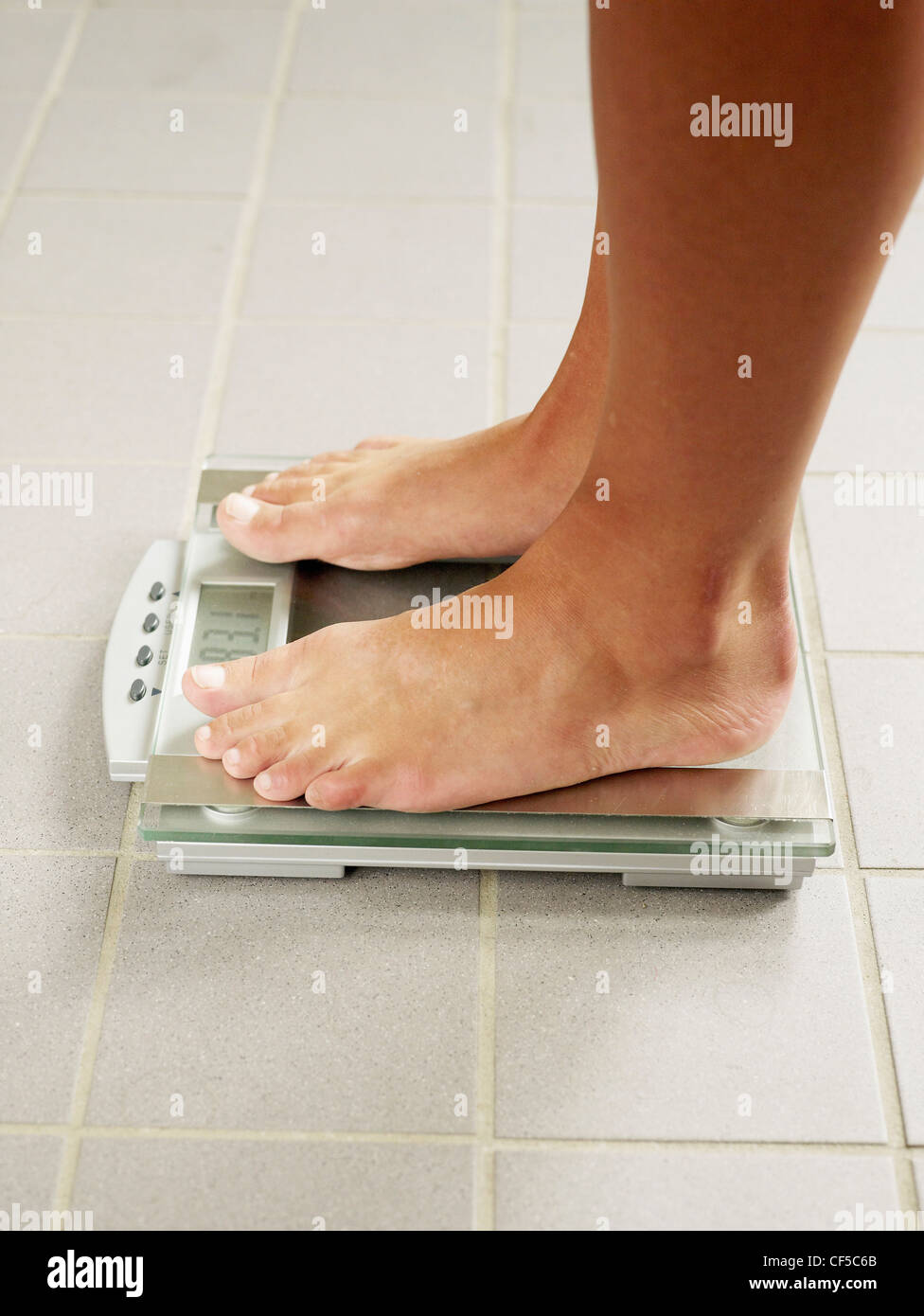 Mid adult woman standing on scales Stock Photo - Alamy