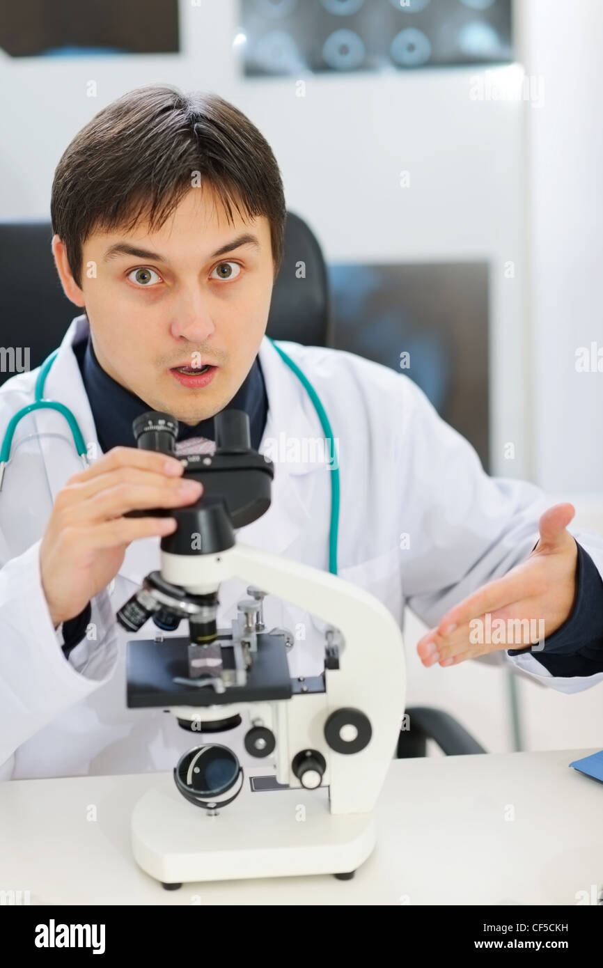Confused male researcher pointing on microscope Stock Photo - Alamy