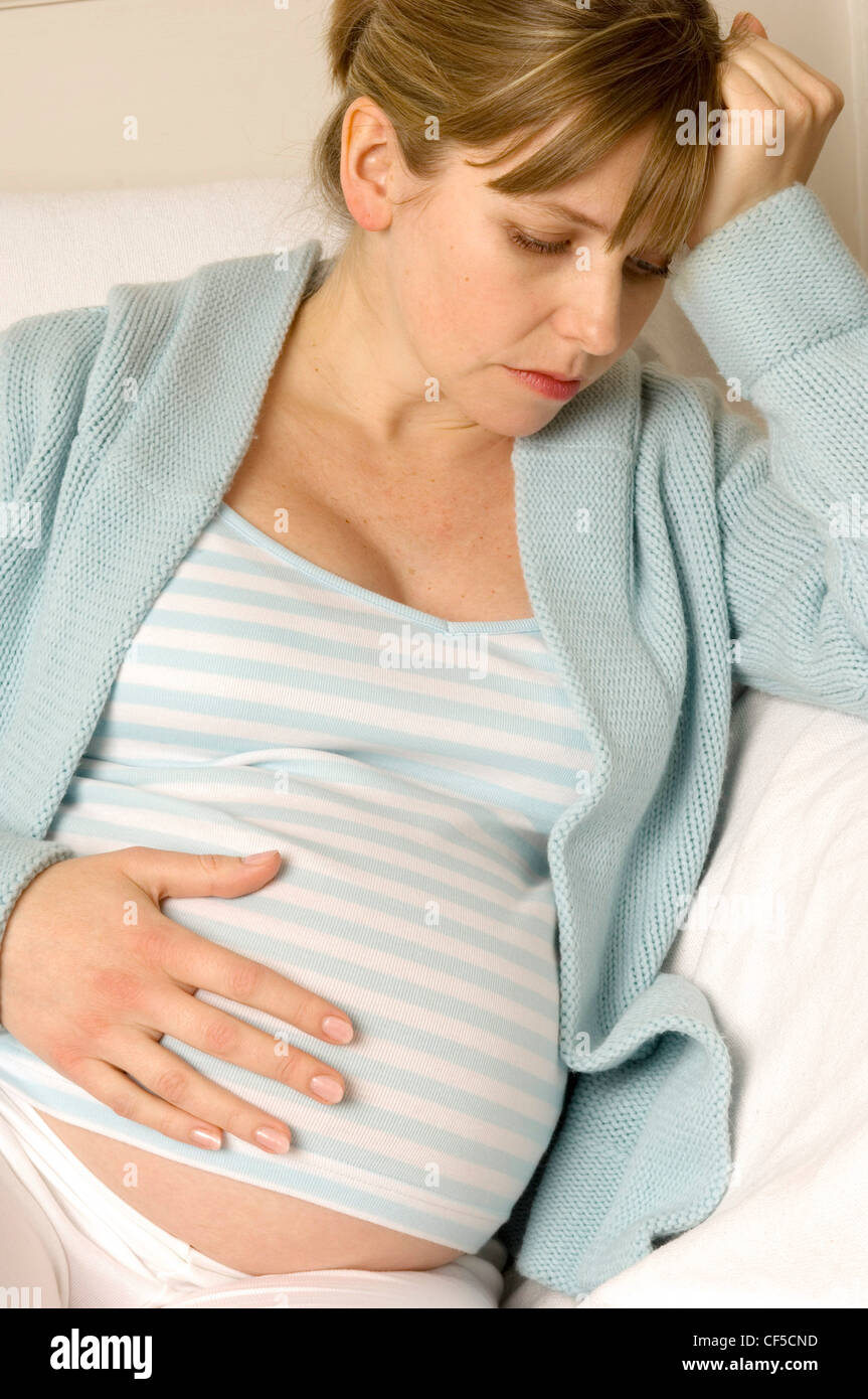 Pregnant Female with hand on bump looking worried Stock Photo - Alamy