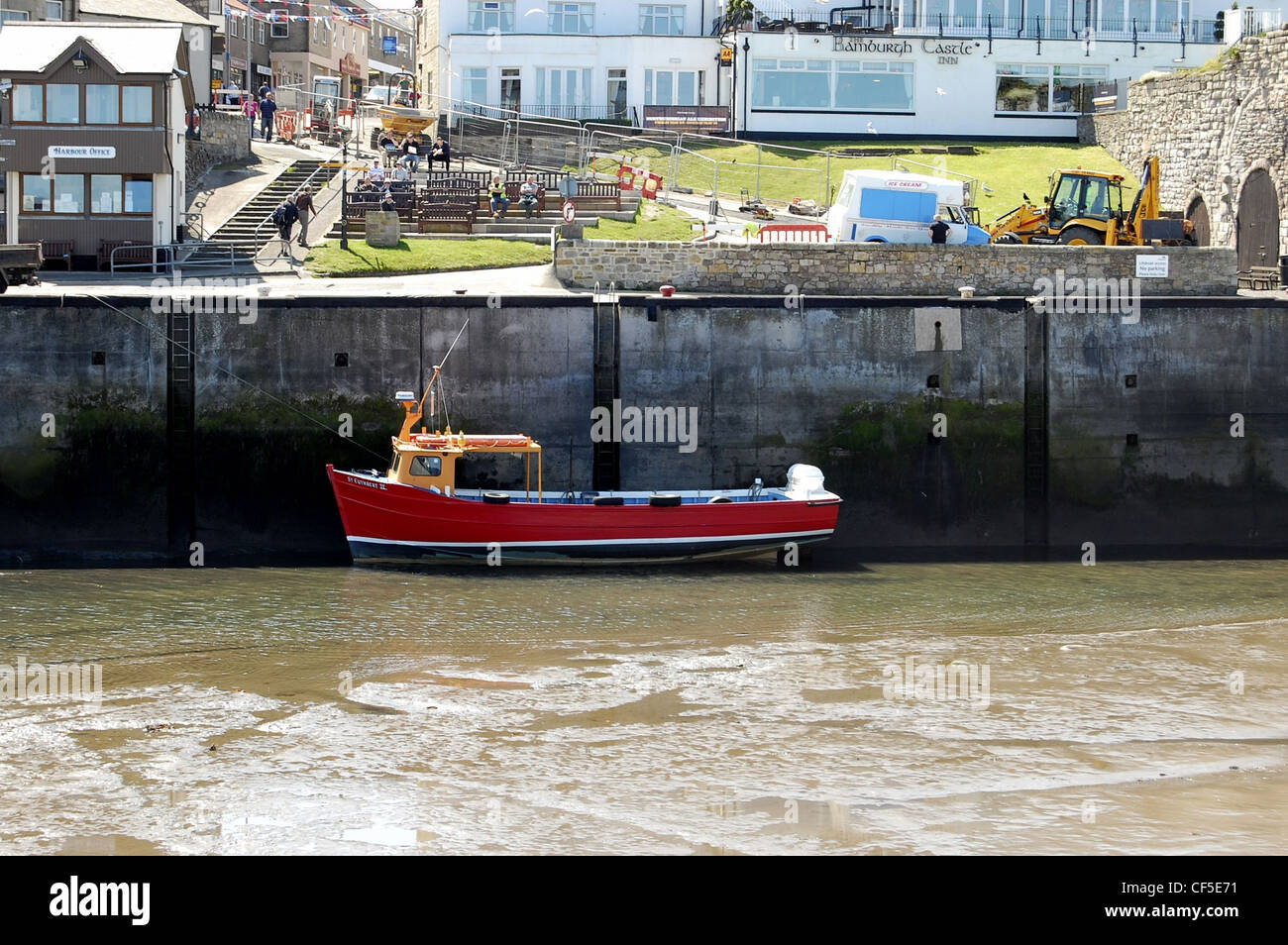 Seahouse harbour at low tide with boat resting on the muddy seabed with ...