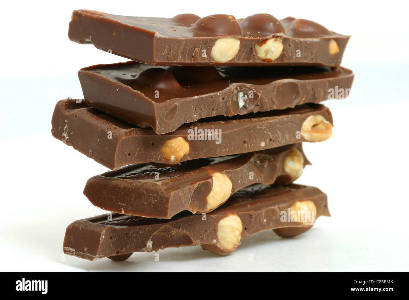 A cut out of a stack of milk chocolate pieces with whole hazelnuts in ...