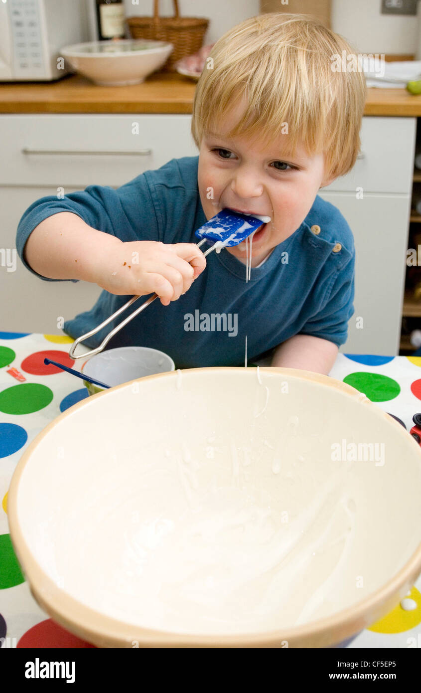 A male child licking icing off the spatual out of a cake bowl Stock ...