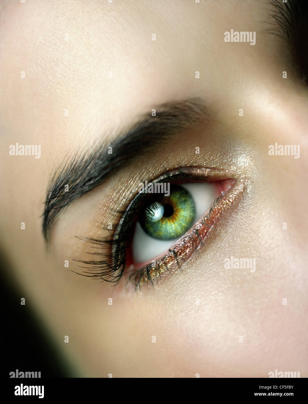 Female wearing gold shimmer eyeshadow, black liquid eyeliner and false ...