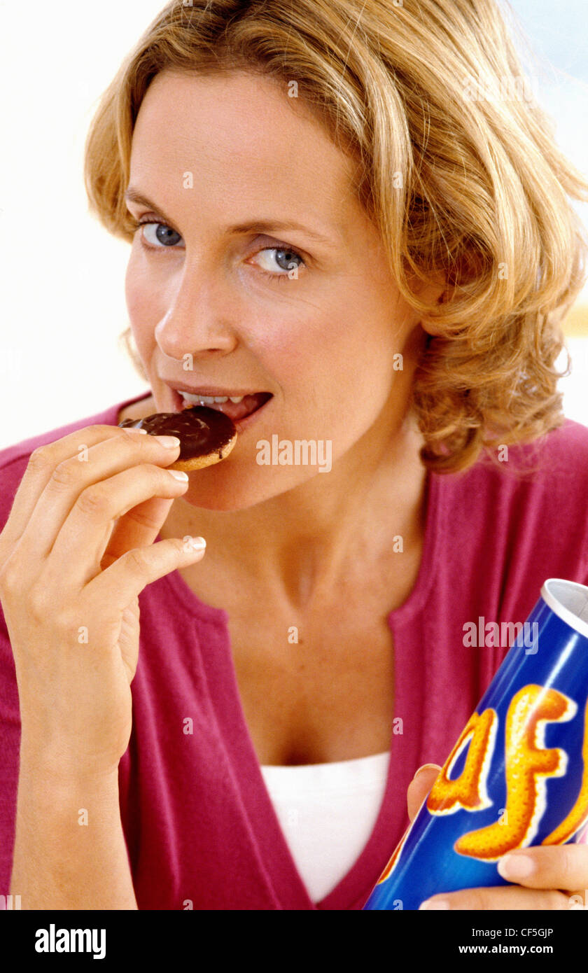 Female with short fair hair, wearing a pink cardigan, eating jaffa ...