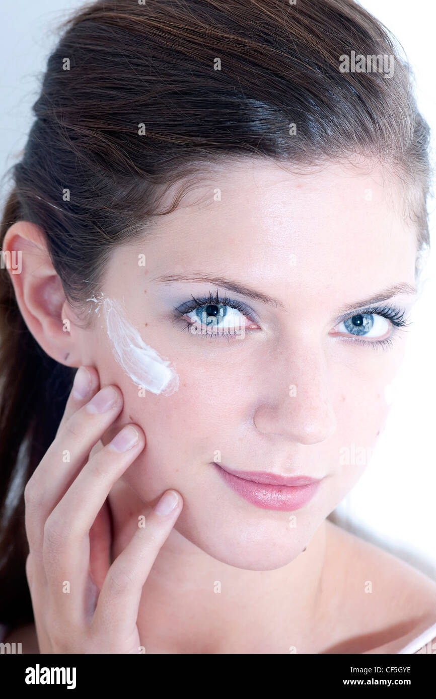 Female with brunette hair off her face, touching face with fingers ...