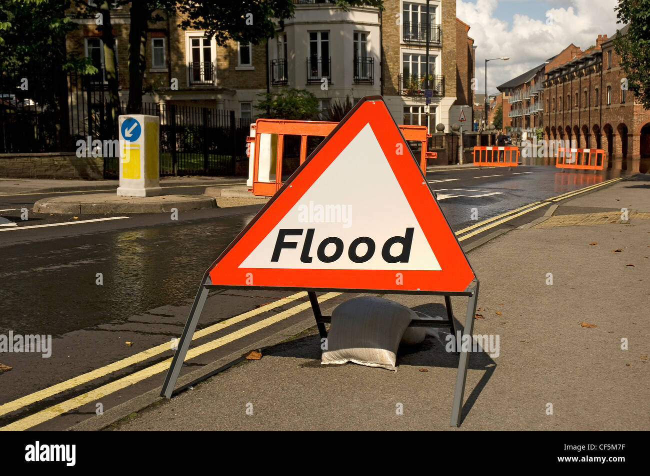 Flood warning sign and barriers across road halting traffic due to ...