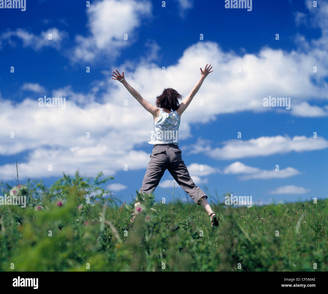 A female doing a star jump in the middle of a meadow Stock Photo - Alamy