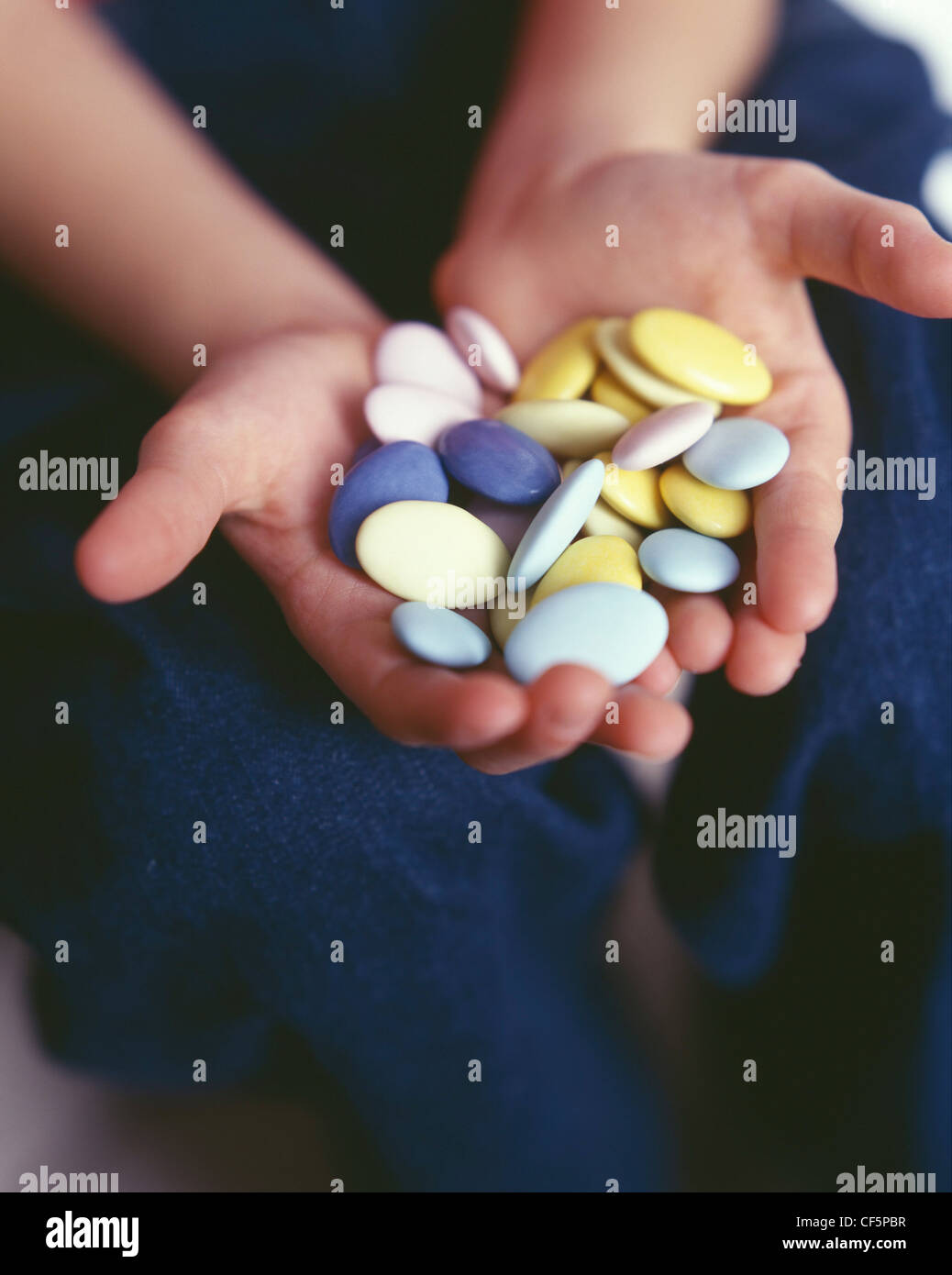 Child's hands cupped, holding multicoloured round sweets Stock Photo ...