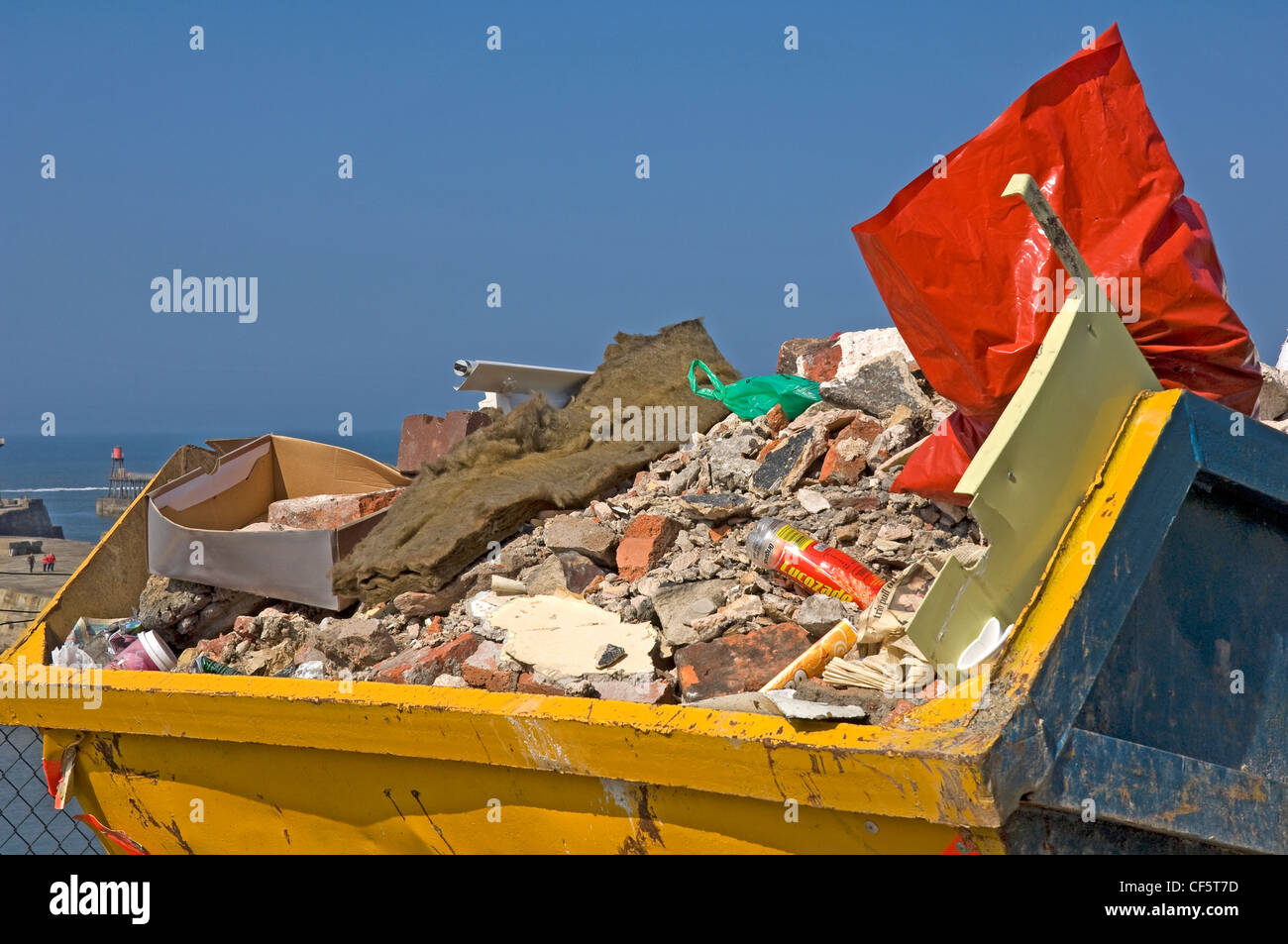 A yellow metal skip filled with builders rubble Stock Photo - Alamy
