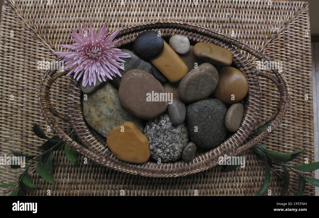 Pebbles with pink flower in basket Stock Photo - Alamy