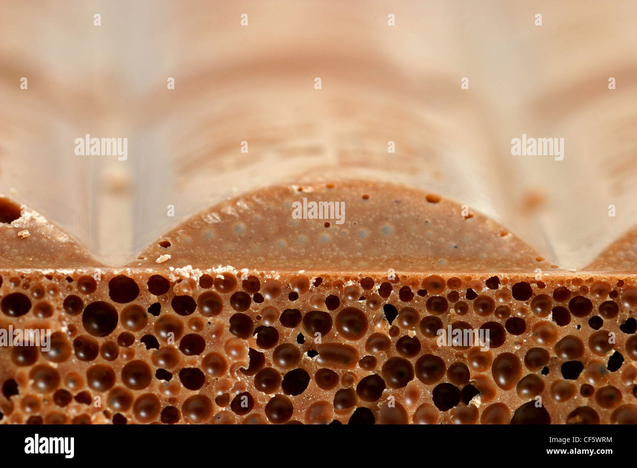 A close up of the side of a bar of milk chocolate with bubbles in it ...