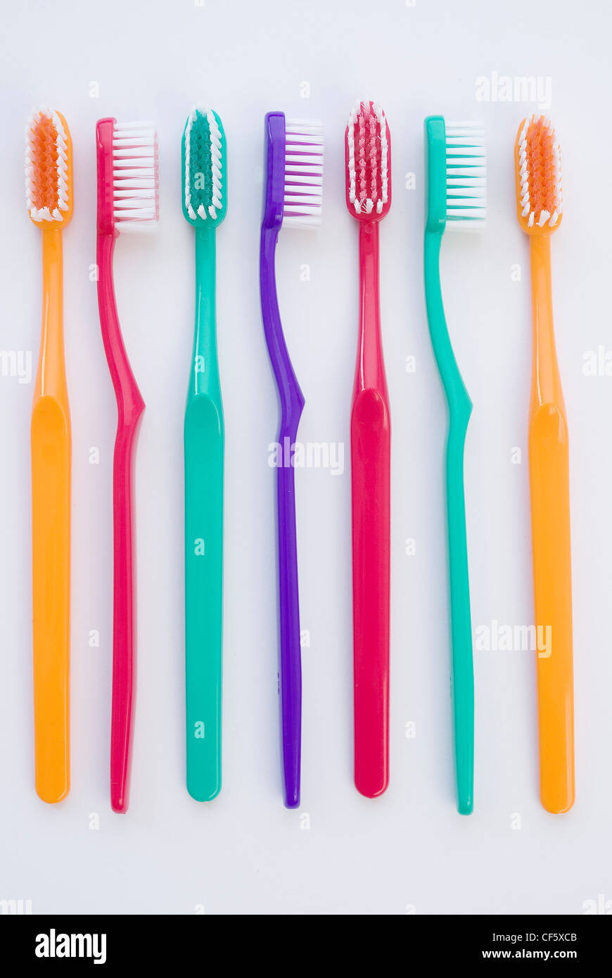 Purple, yellow, green and red toothbrushes at different angles in a row ...
