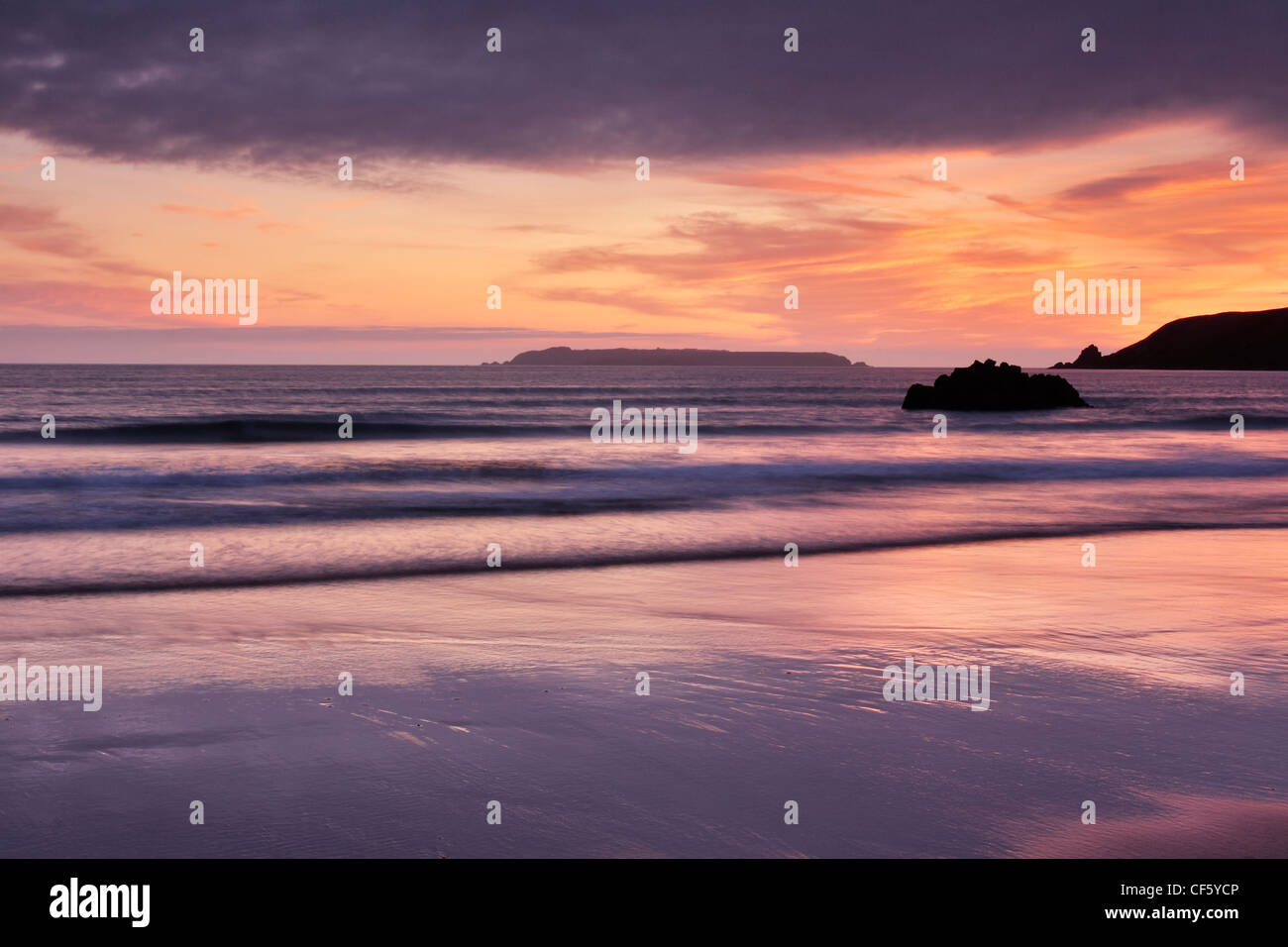 A colourful sky at sunset reflected in the wet sand of the beach at ...