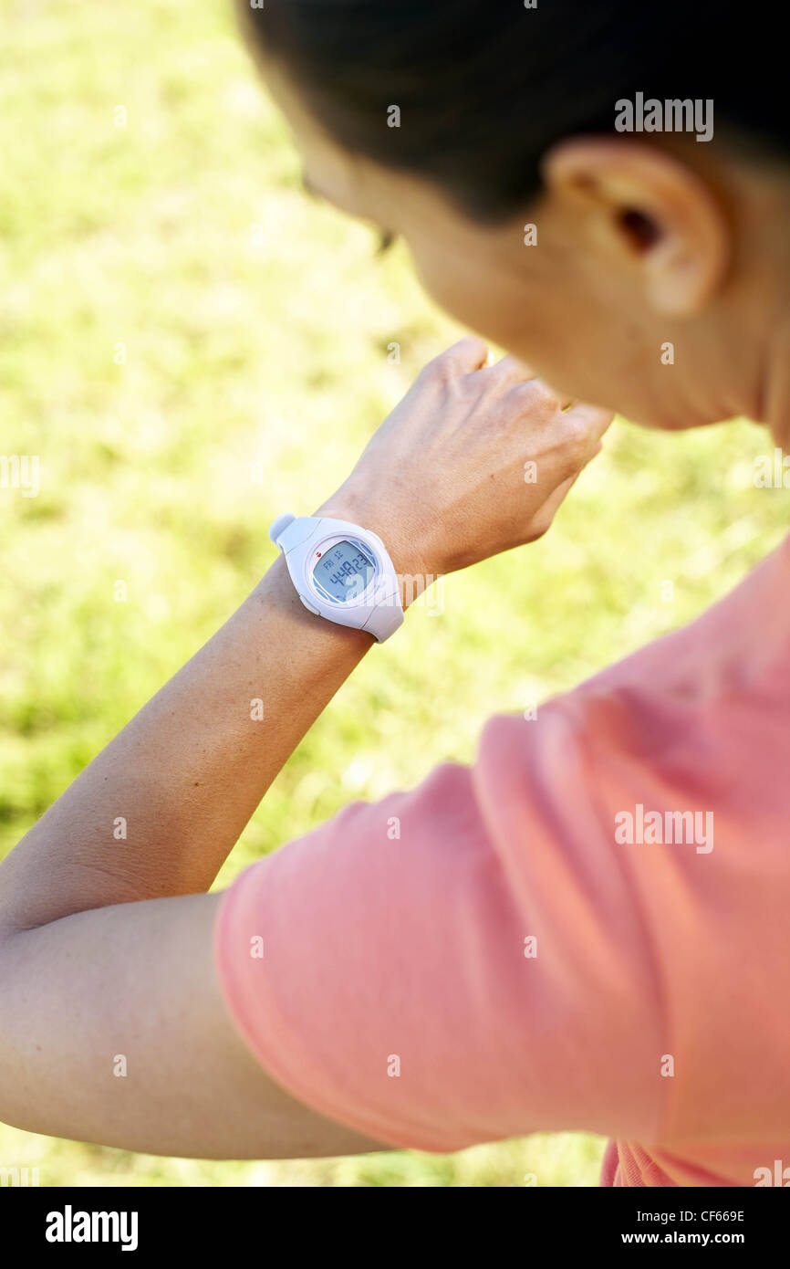 Female wearing salmon colour t shirt looking at sport watch Stock Photo ...