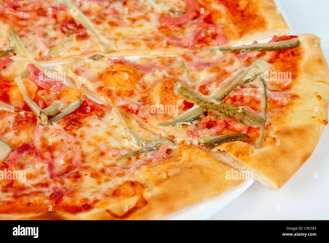 pizza closeup with boiled sausage, ham, marinated gherkin and ...