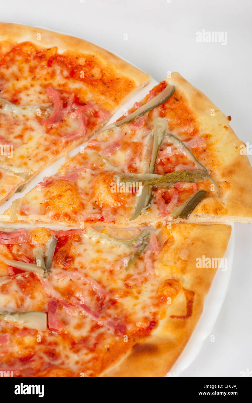 pizza closeup with boiled sausage, ham, marinated gherkin and ...