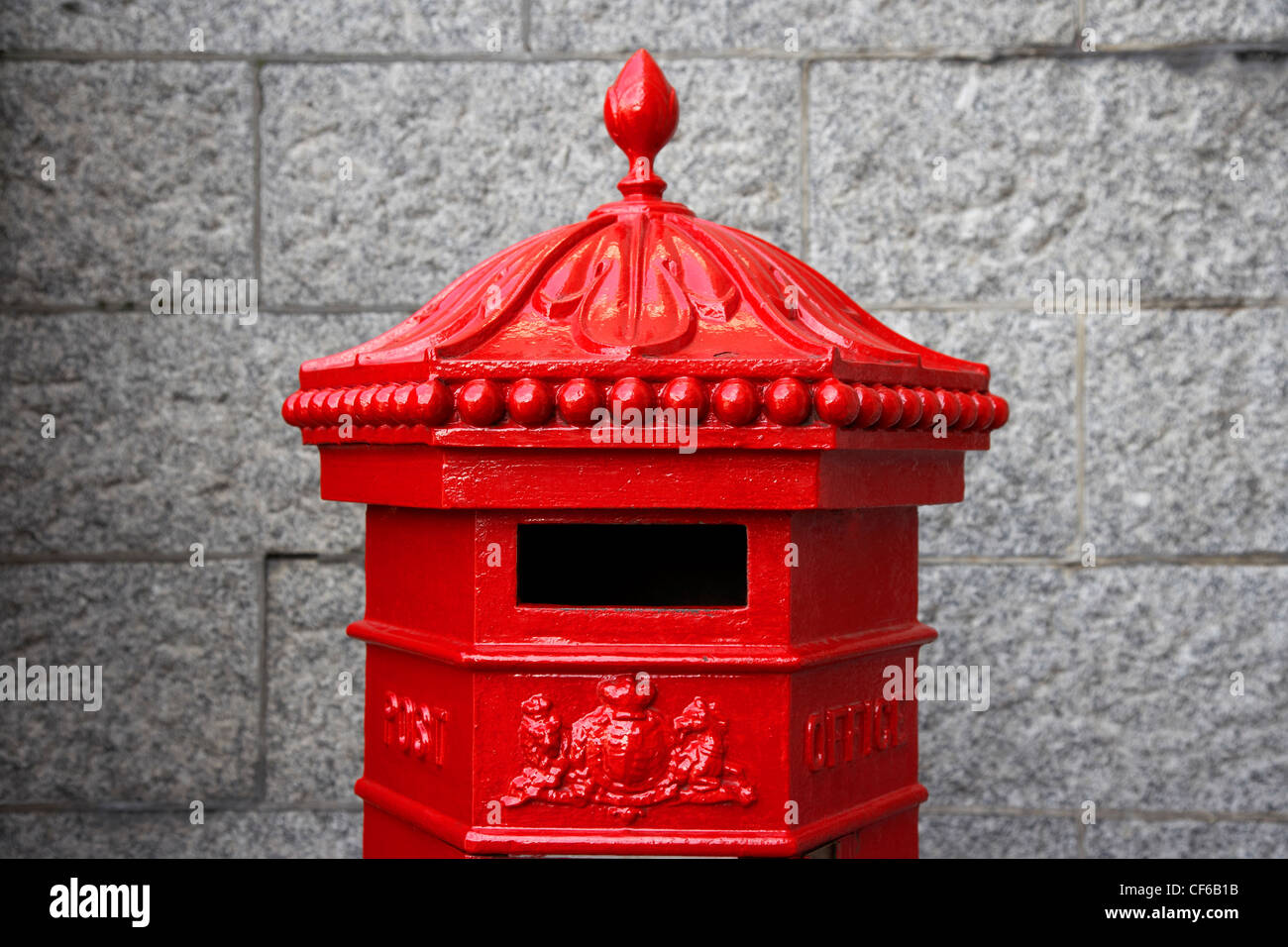 A close up of a traditional red post box beside a wall in Tower Bridge ...