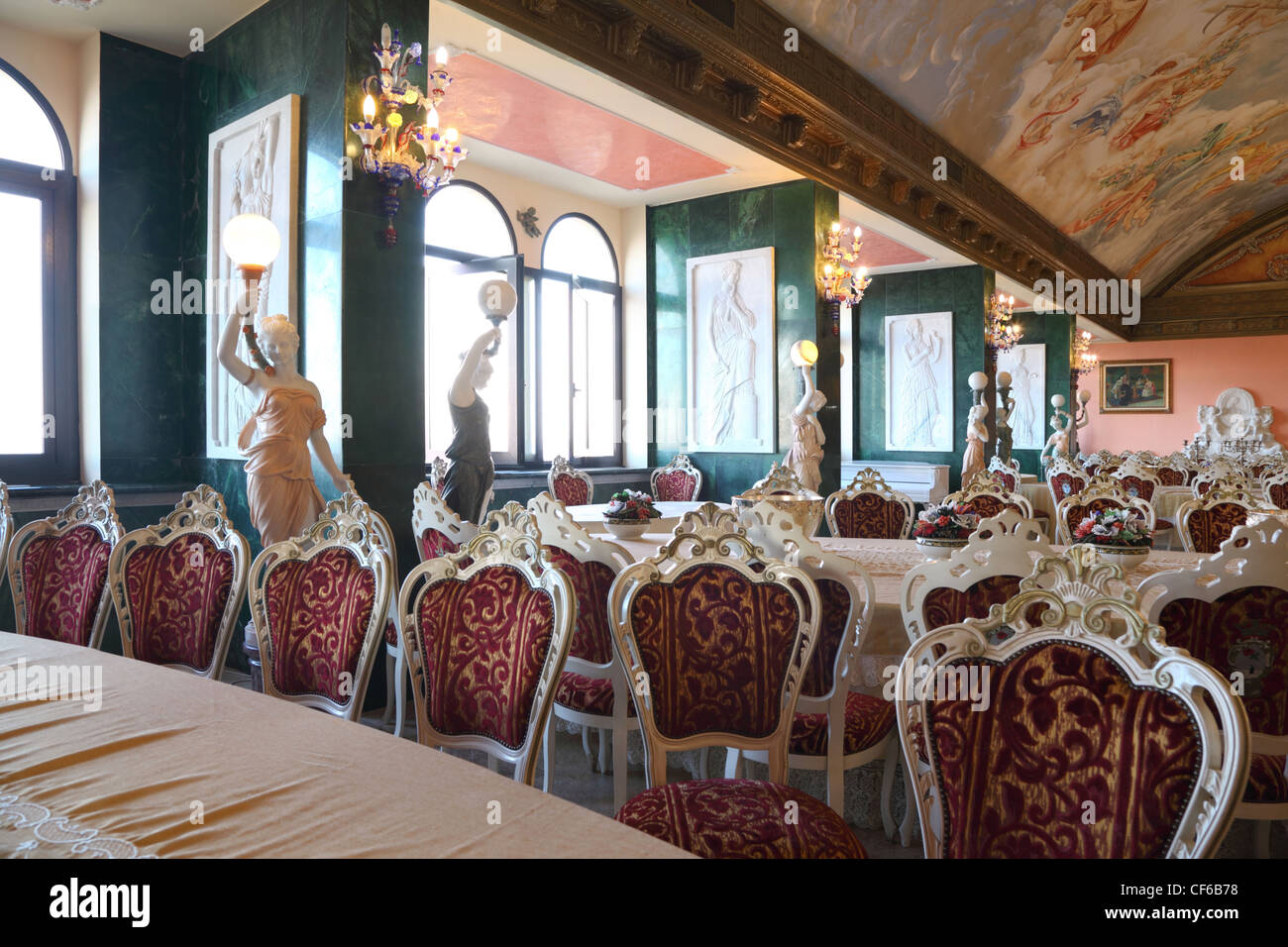 Large dinner hall in palace with rich interior and ancient statues ...