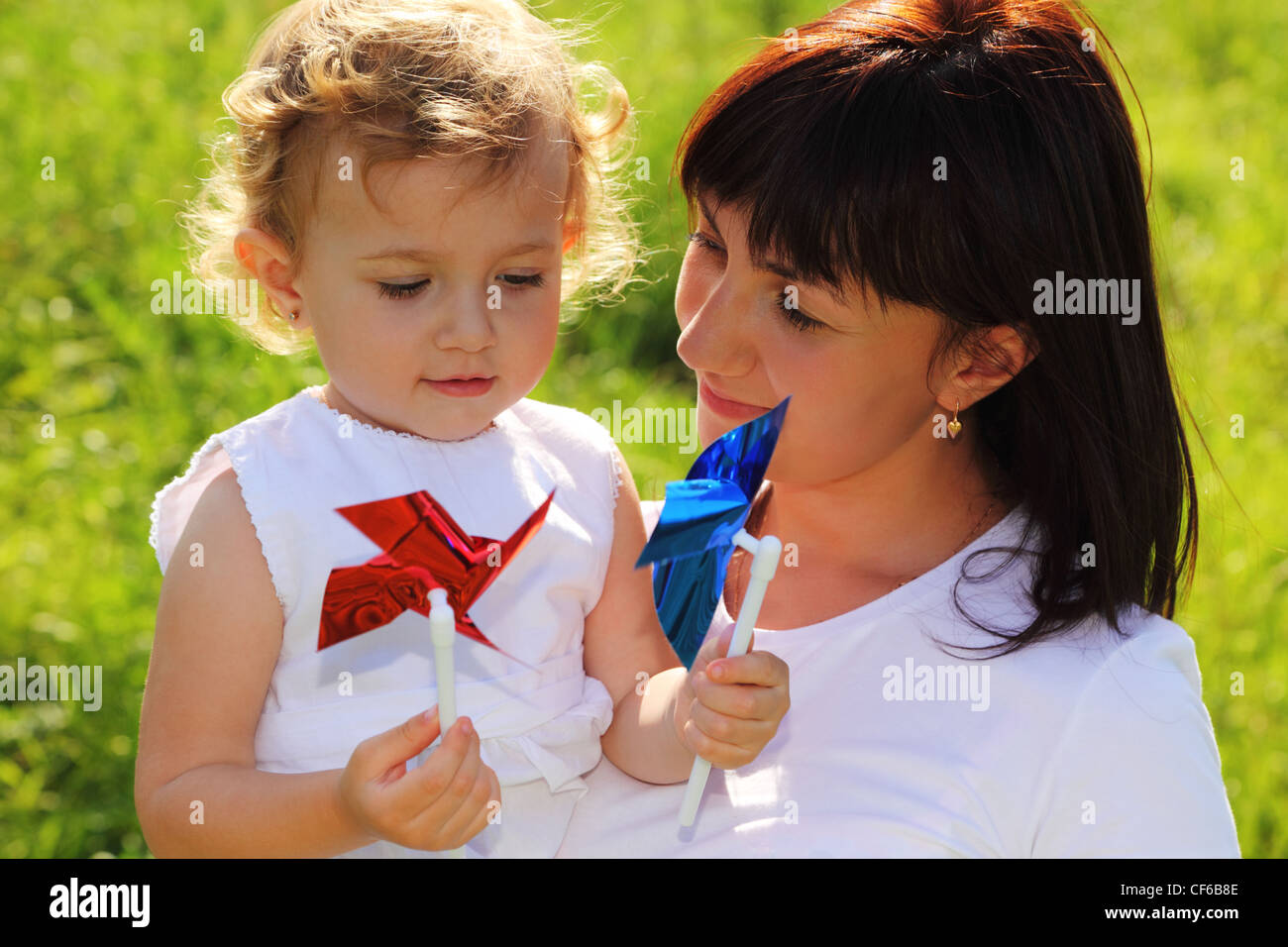 Mother keeps the little girl with two colorful pinwheels Stock Photo ...