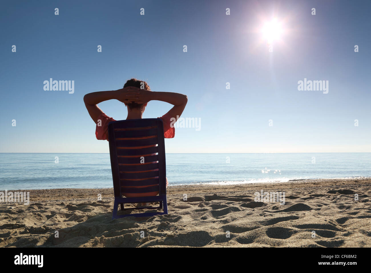 Woman sits on plastic chair heaving up hands for head by person to sea ...