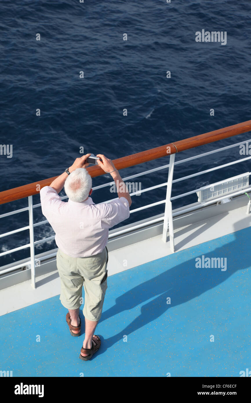 man with compact photo camera standing on deck of cruise ship and ...