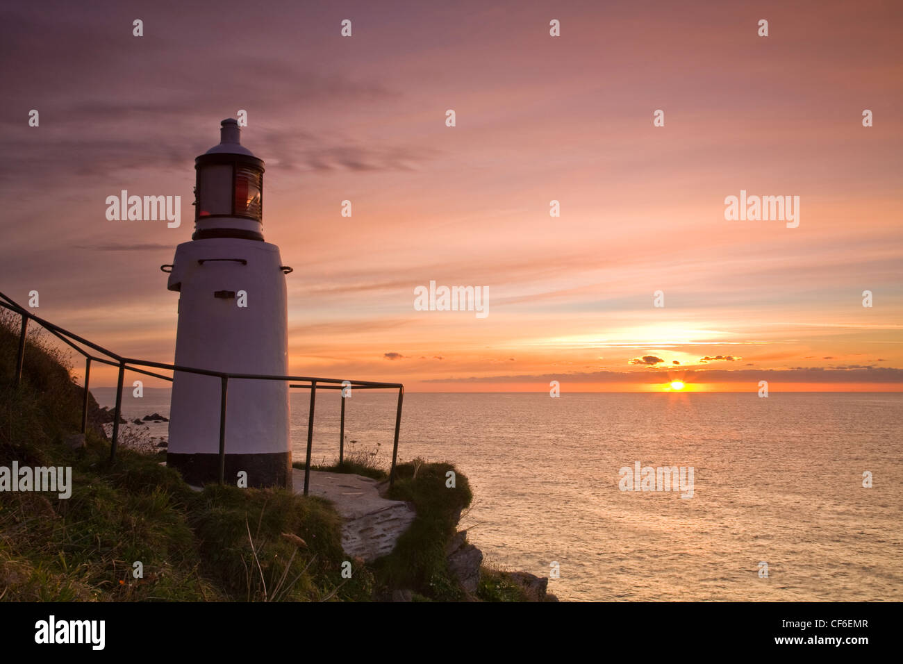 Polperro lighthouse in the foreground as the sun rises above the ...