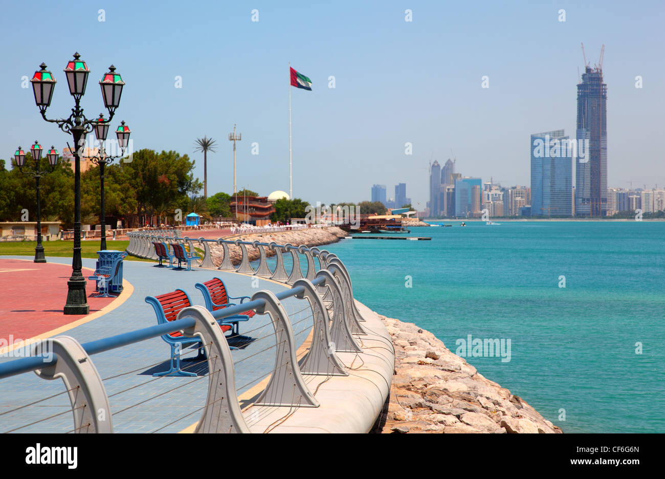 Red benches in park on the seafront against the backdrop of Abu Dhabi ...