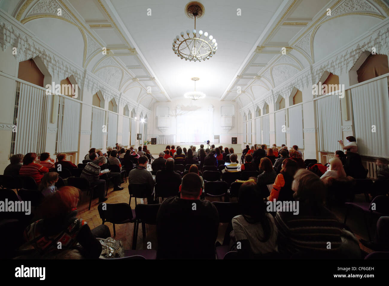 Dark hall filled with audience with illuminated scene, view from the ...