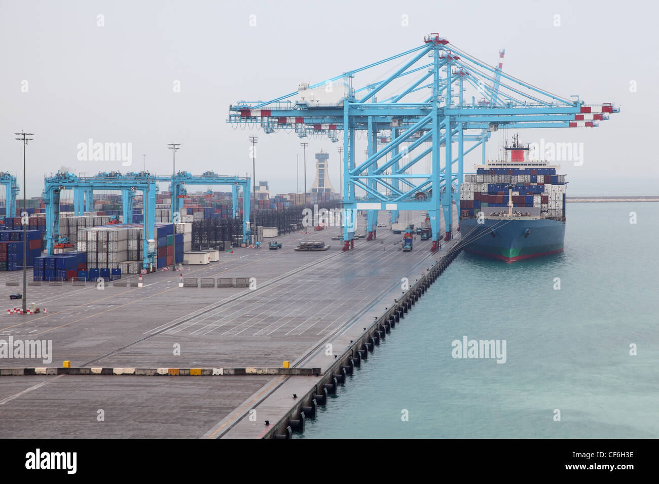 Men load big cargo boat docked to industrial port with blue cranes ...