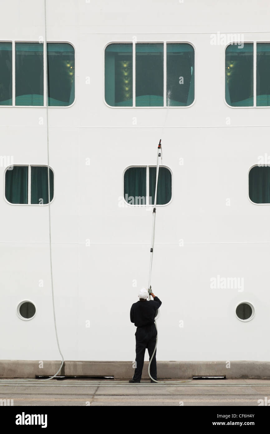 seaman standing in dock and cleaning window of big white ship Stock ...
