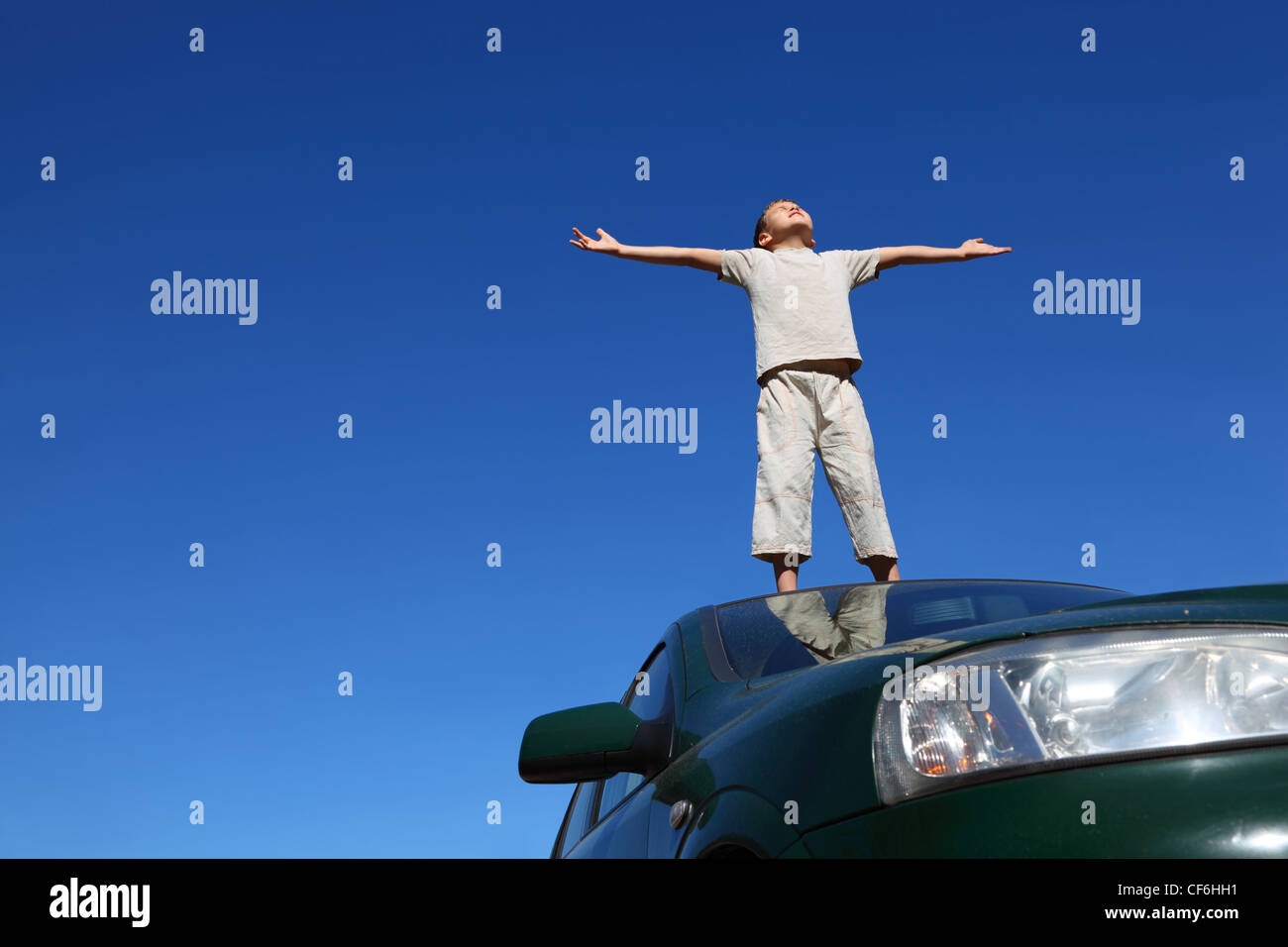 Boy stands on head of car widely placing hands and heaved up face ...