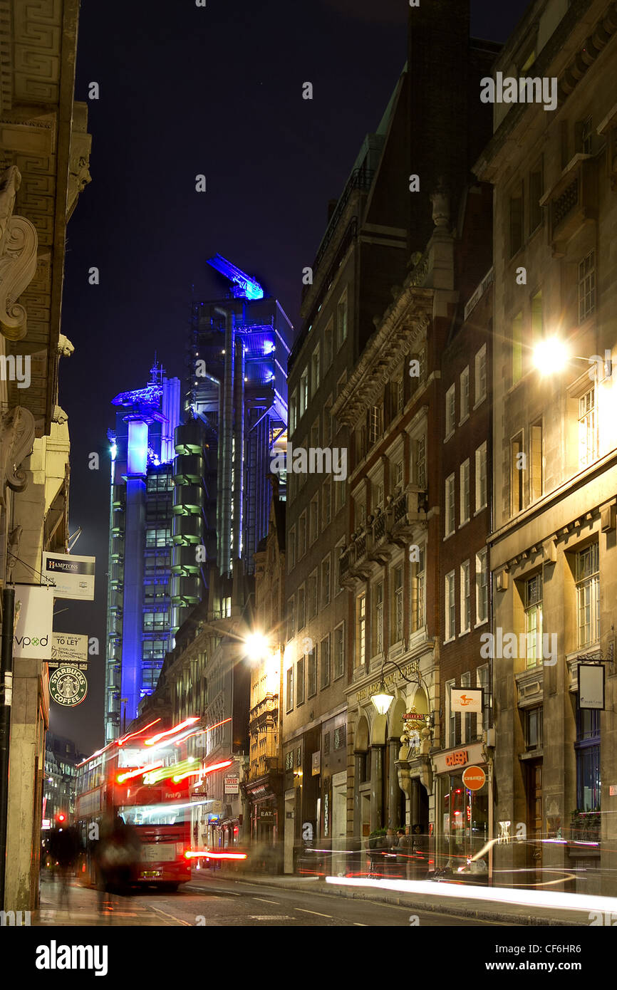 Lloyds of London building at night and movement trail of red London bus ...