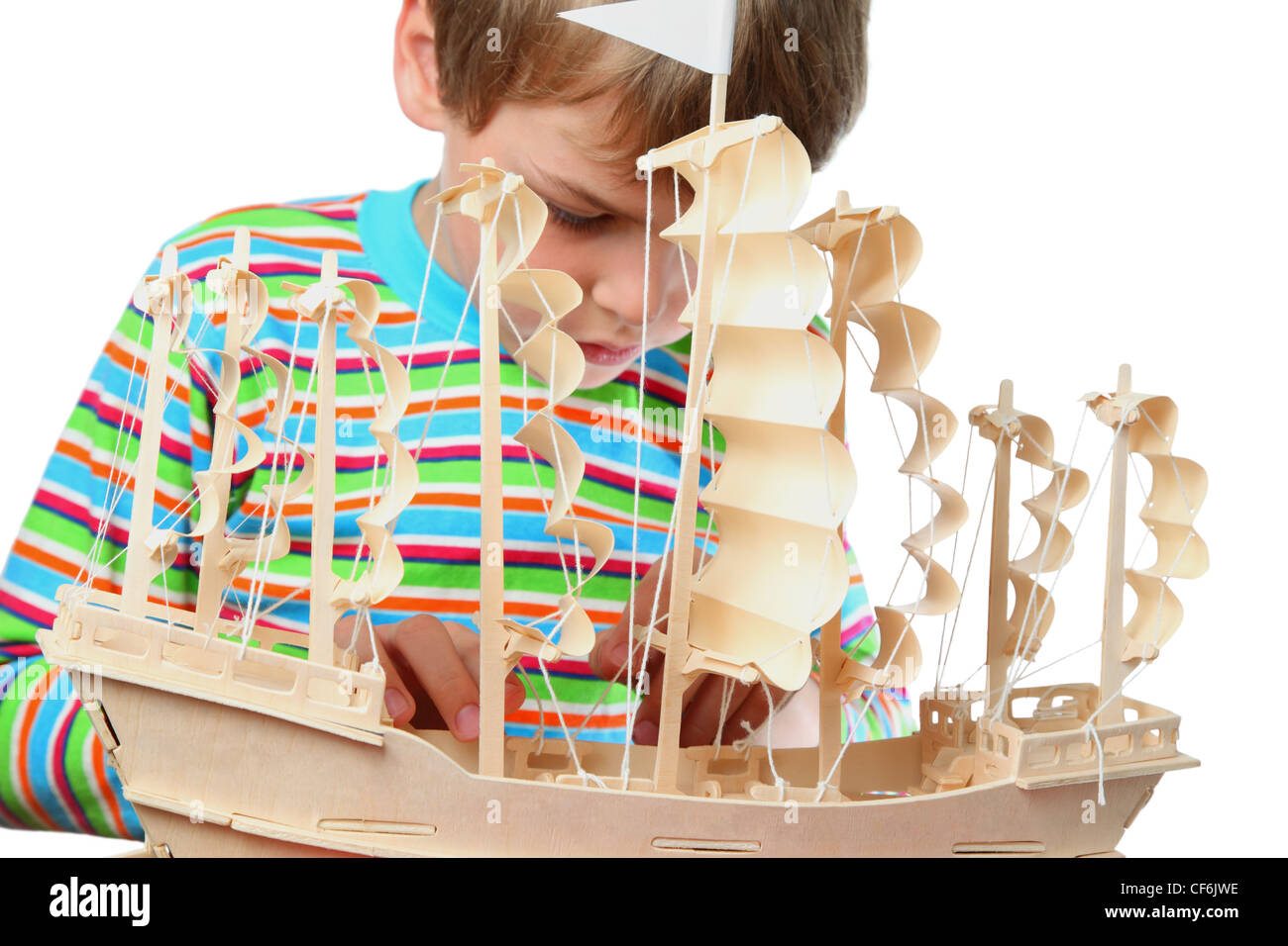Small boy in striped shirt work with zeal on hull of artificial ship ...