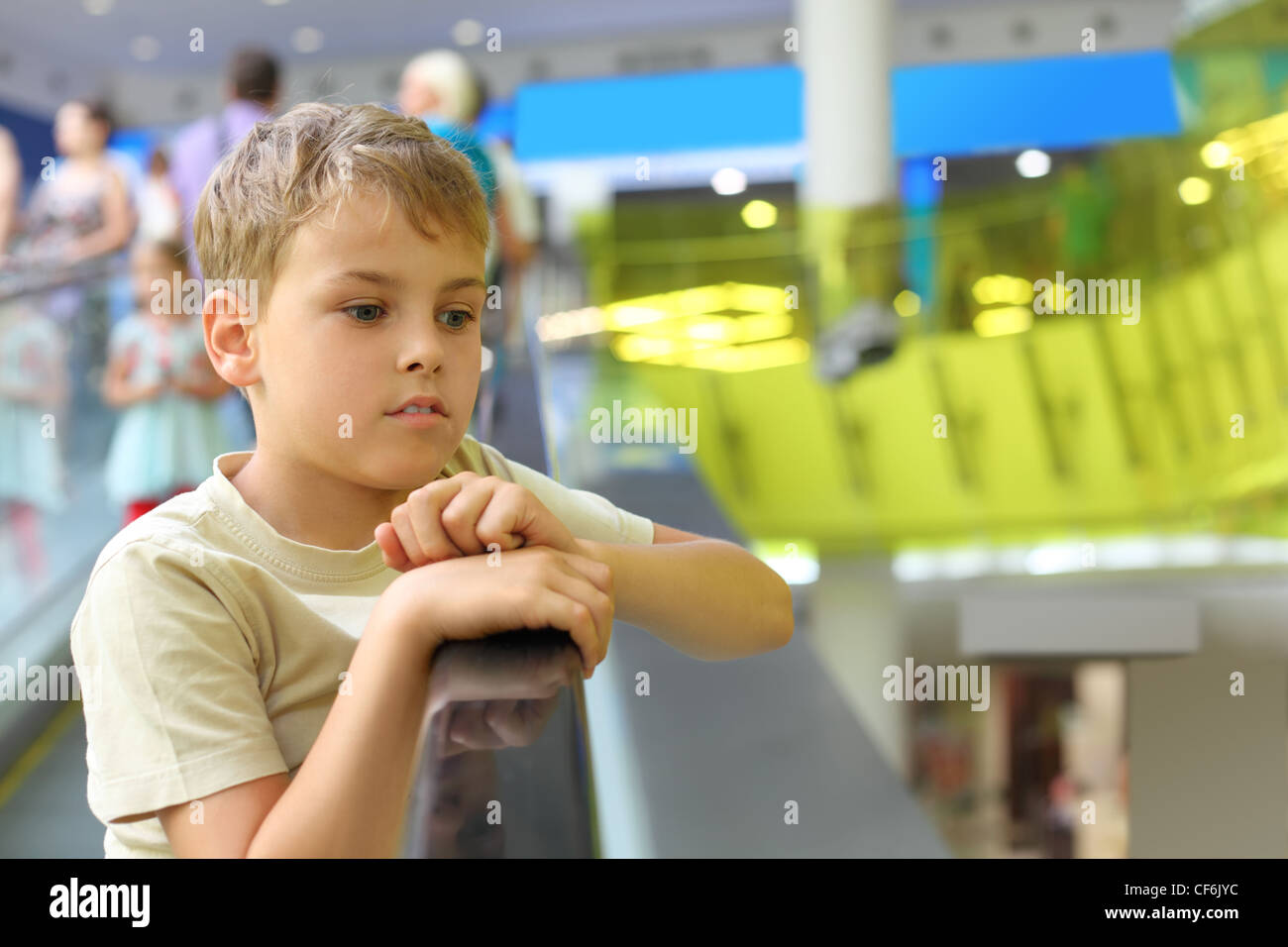 little serious boy standing on escalator and moving up, looking at side ...