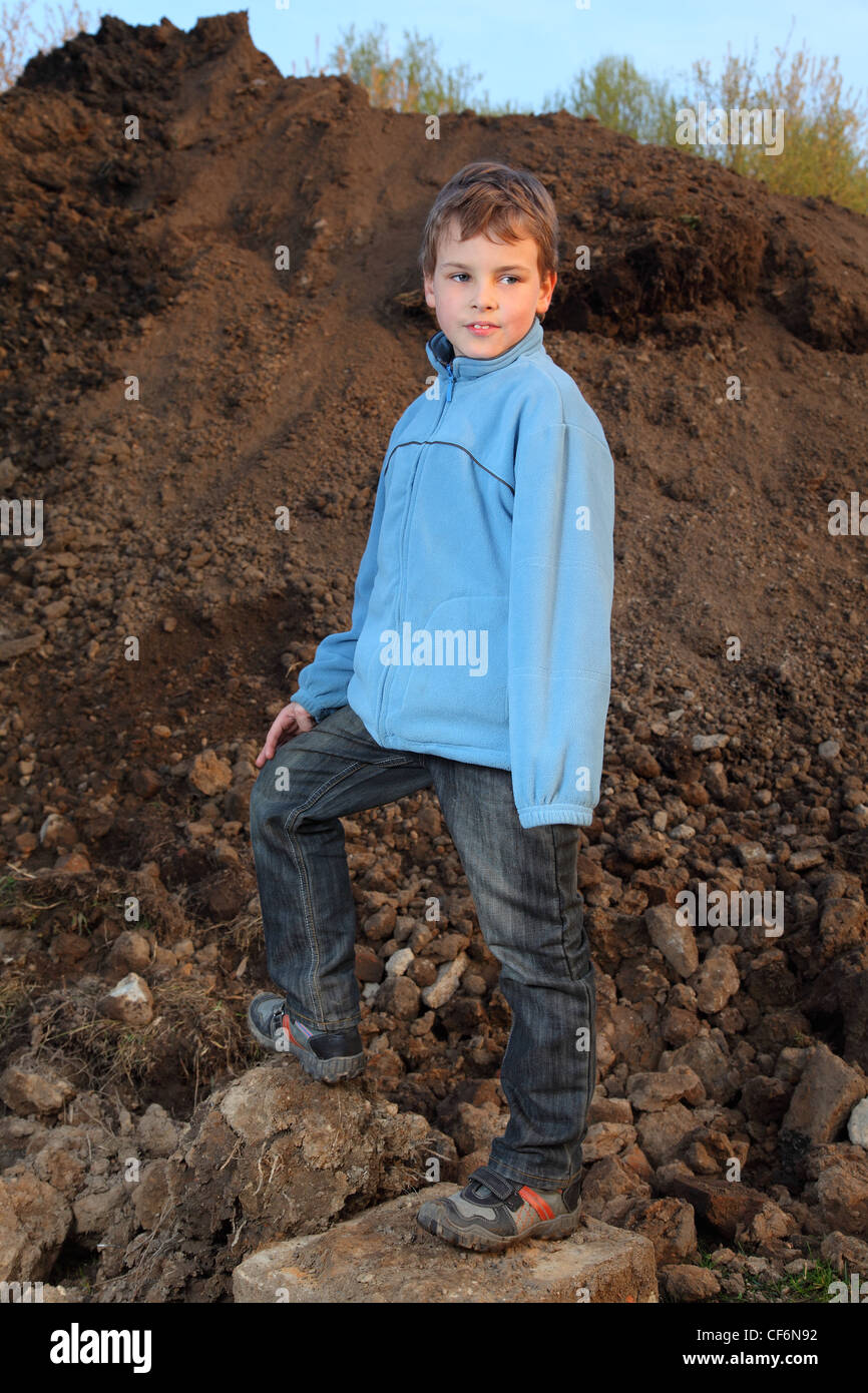 Little boy in blue jacket stands on earthen embankment at evening Stock ...