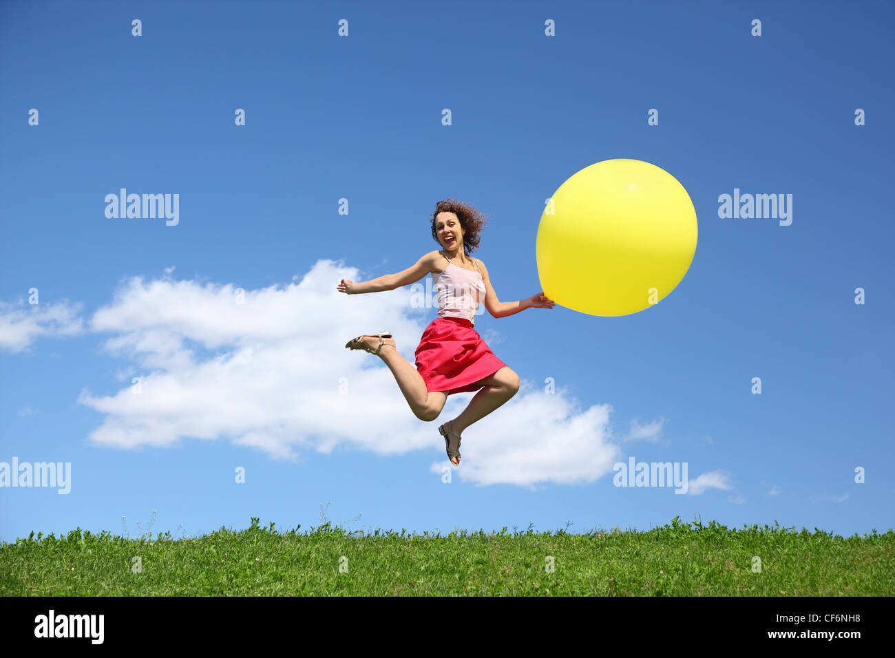 Woman jumps away from grass with large inflatable ball and laughs on ...