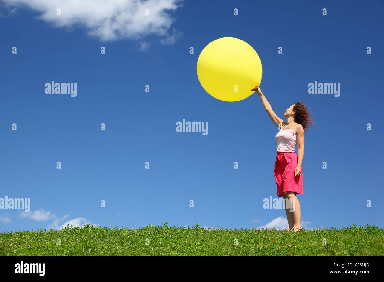 Woman stands in summer on grass and starts large inflatable ball in ...