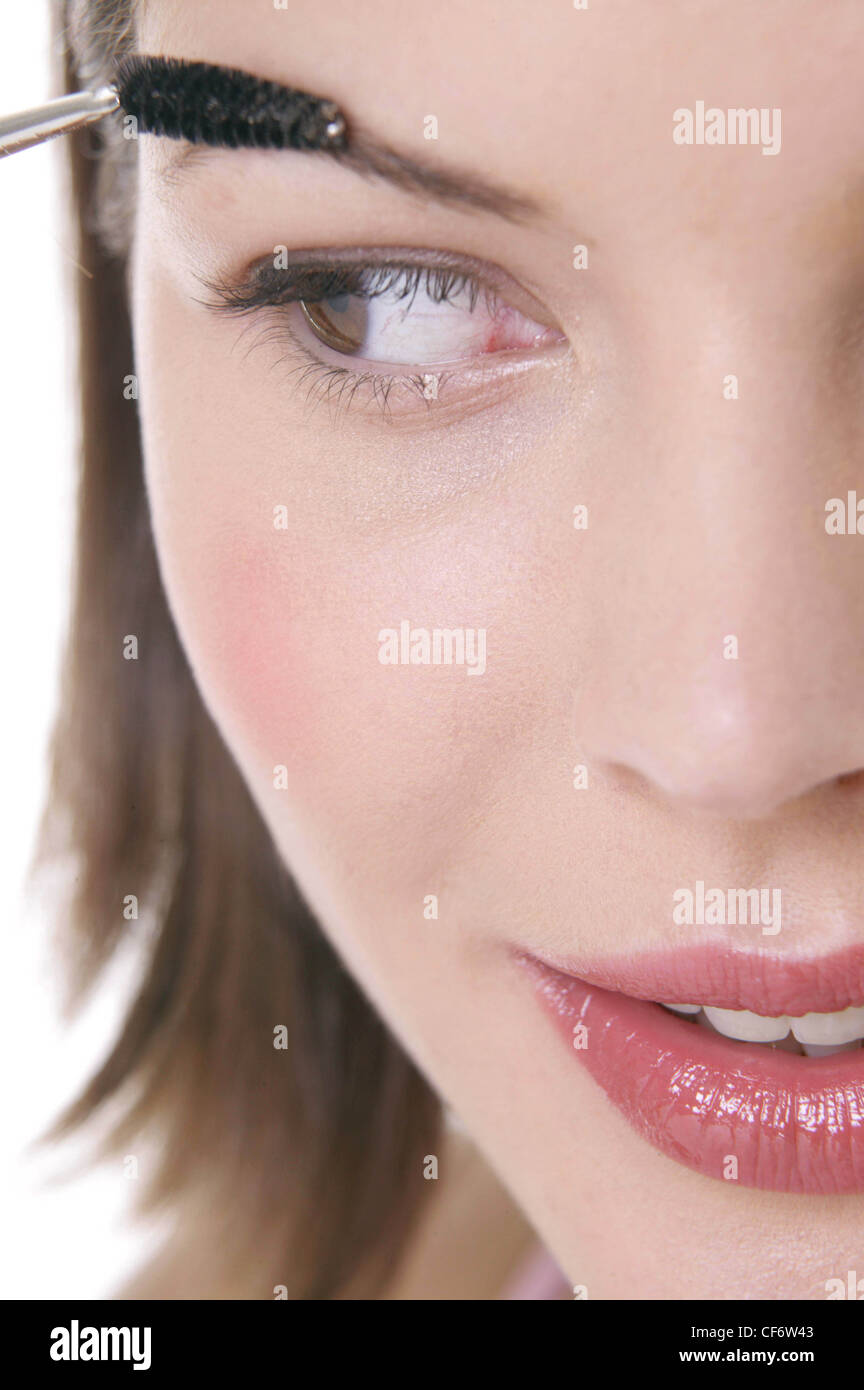 Female shoulder length brunette hair holding silver eyebrow brush to ...