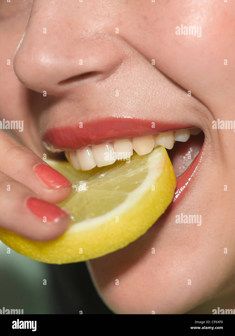 Cropped lower face of Female biting slice of lemon Stock Photo - Alamy
