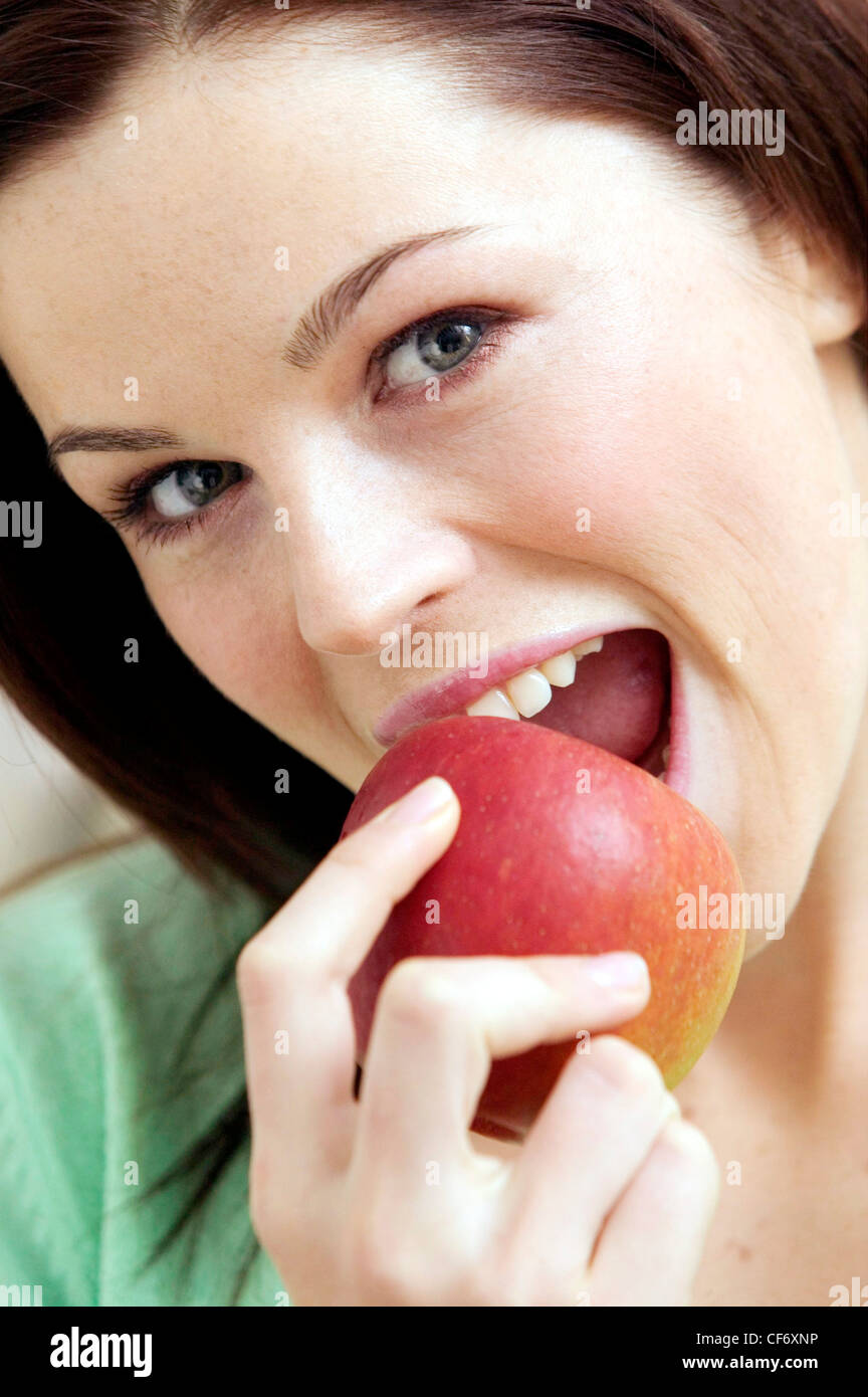 Female with long brunette hair wearing green v neck top eating apple ...