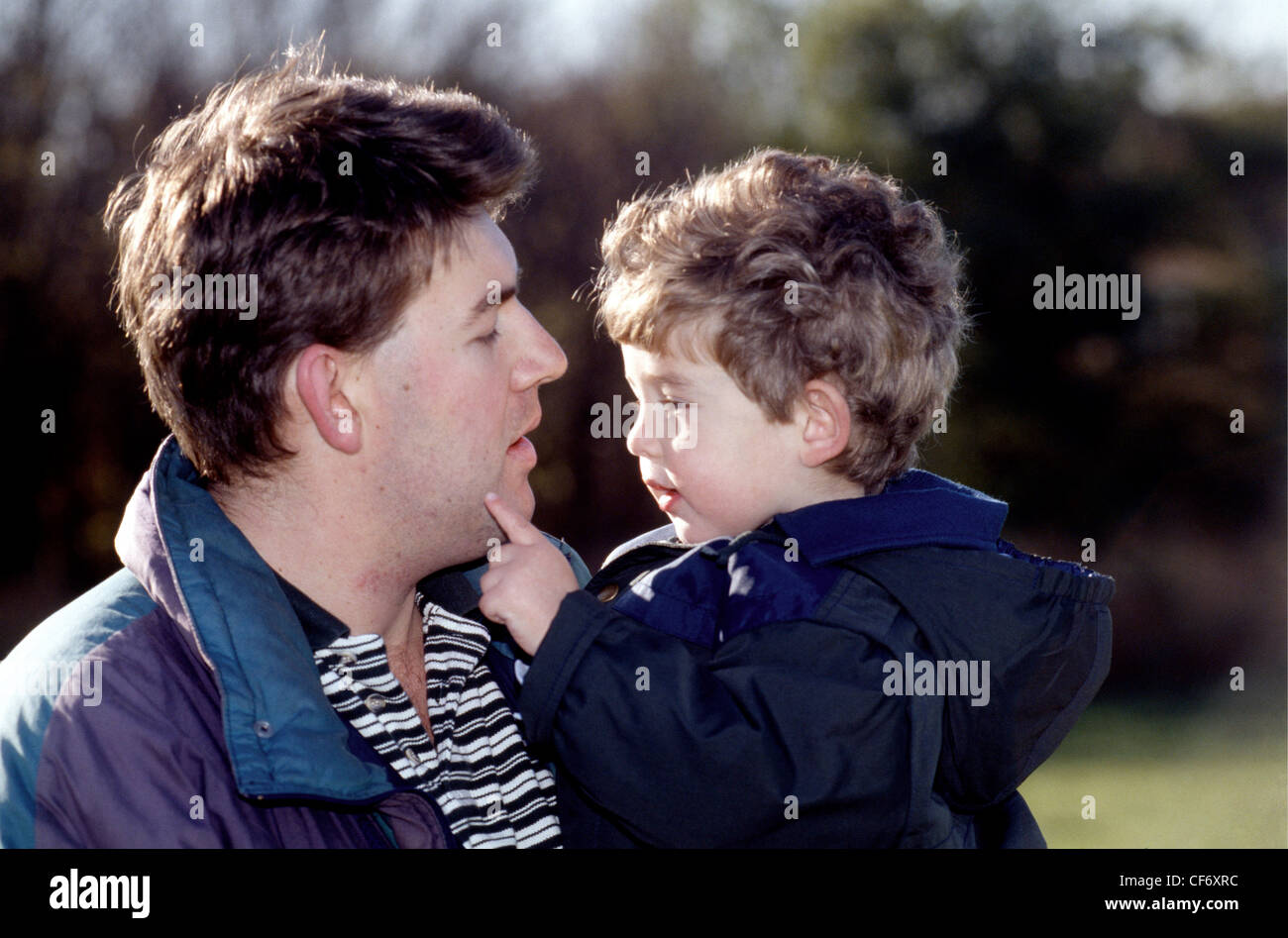 Male and child looking at each other unsmiling, adult male on left ...