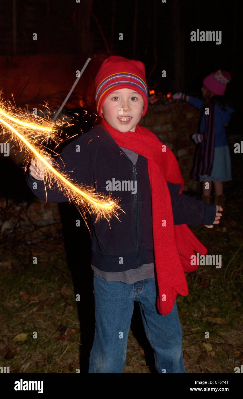 Night time image of male child swinging a sparkler one hand, looking ...
