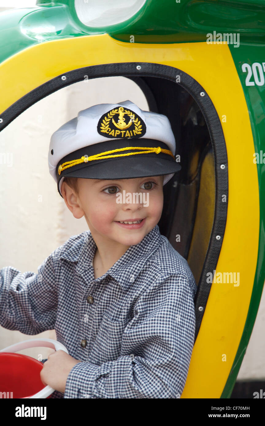 Male child, blue and white check shirt, captain cap, at fairground, on ...