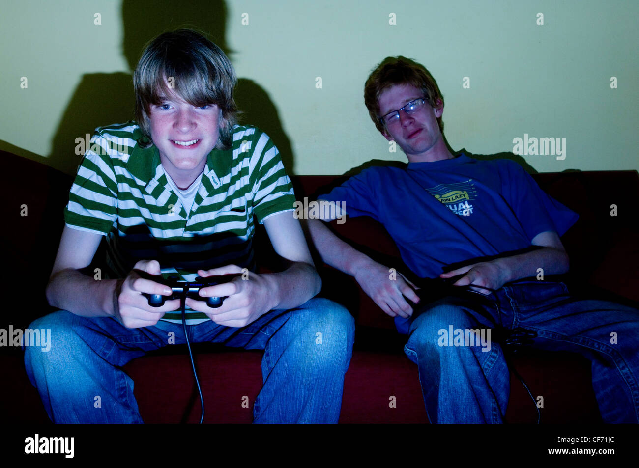 Two male teenagers sitting on sofa playing computer game Stock Photo ...