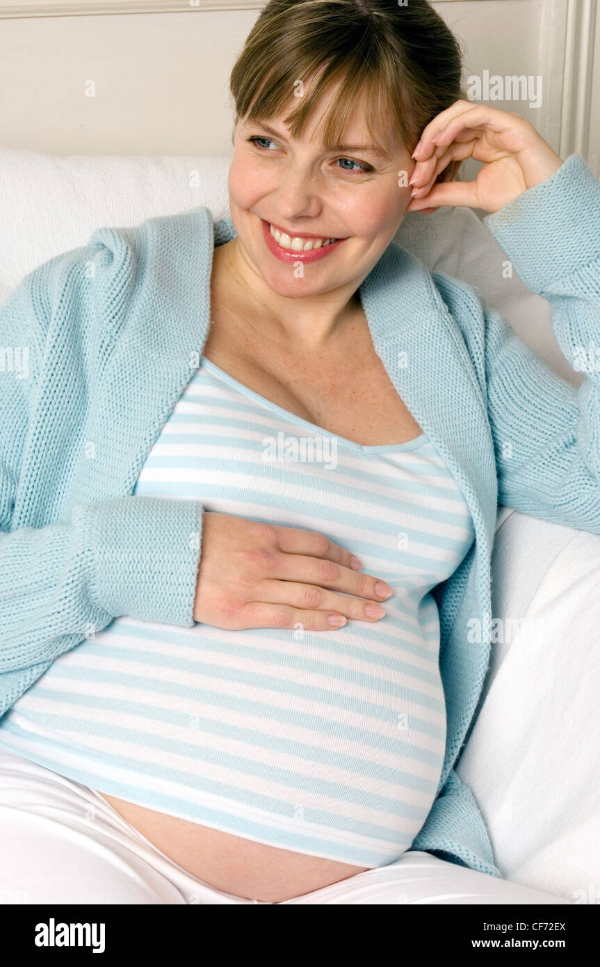 Pregnant Female with hand on bump smiling Stock Photo - Alamy