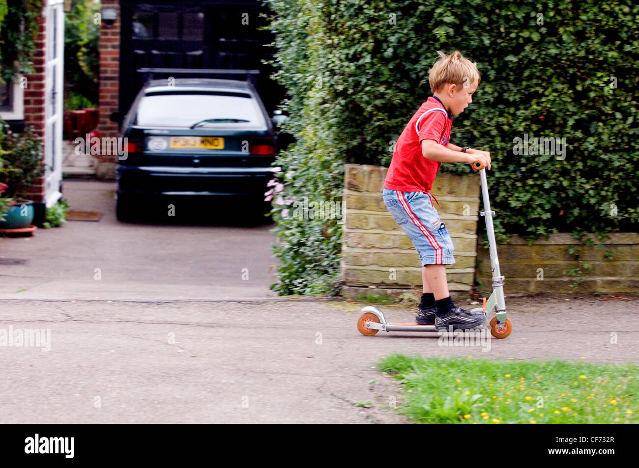 A young male riding a scooter down a pavment Stock Photo - Alamy
