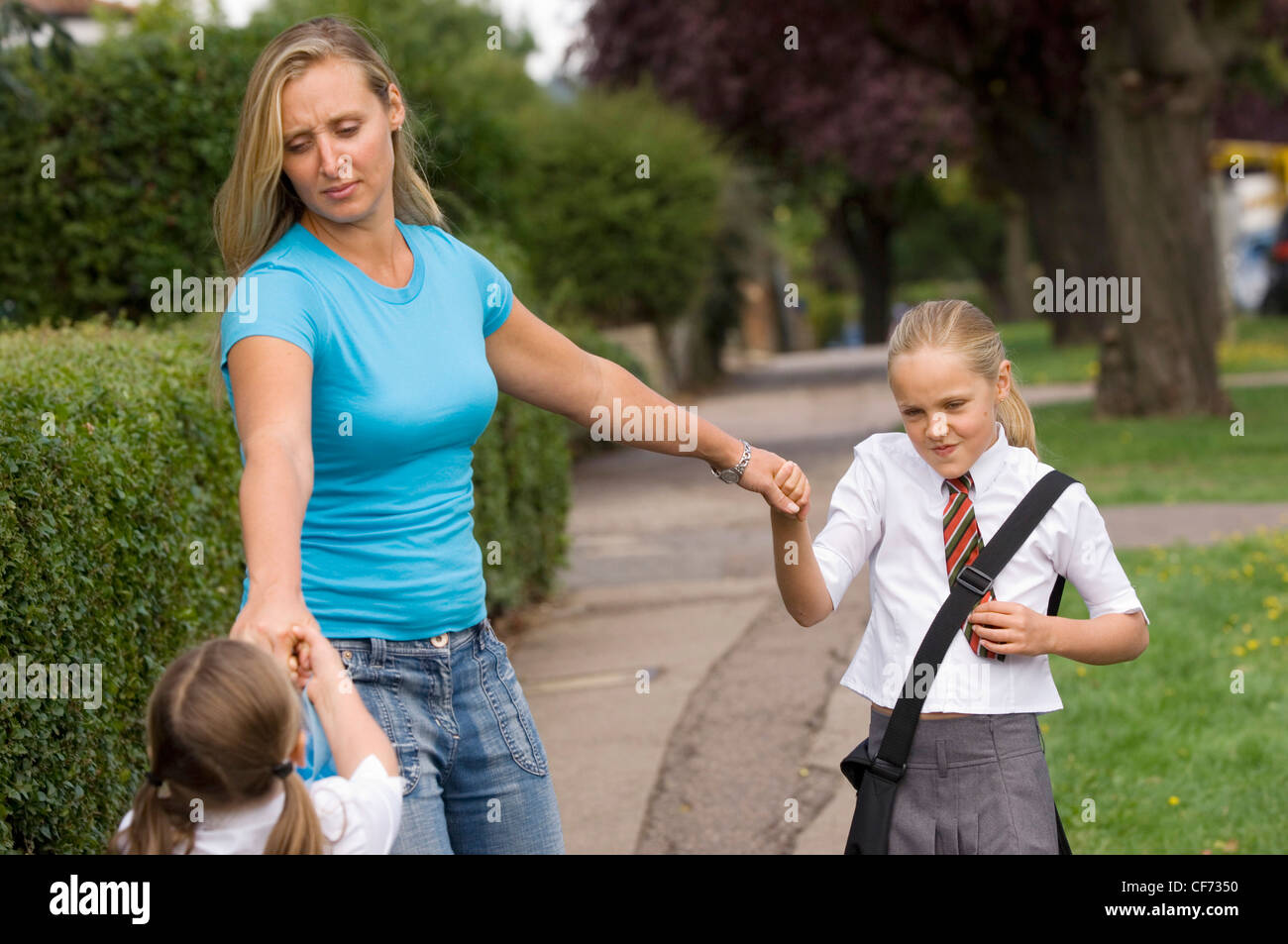Mother holding the hands of her daughters, walking to school, children ...