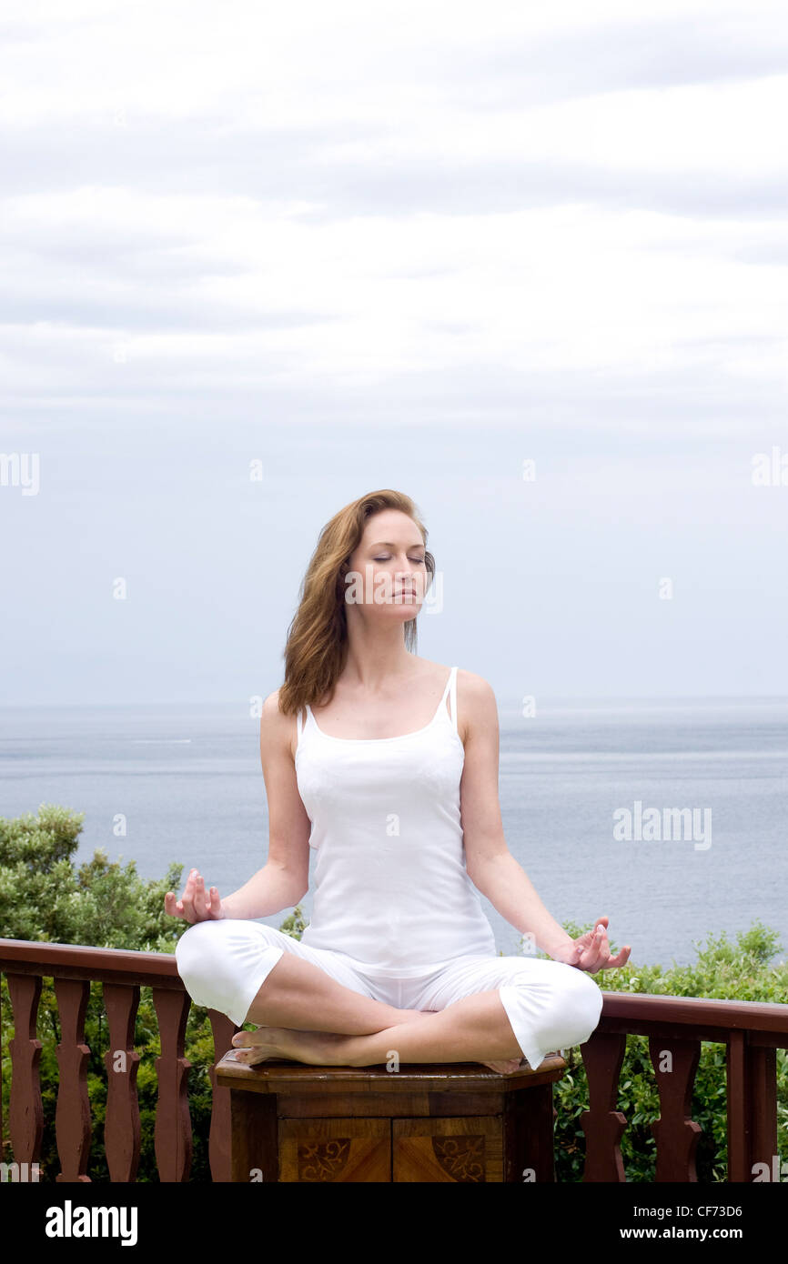Female wearing a white vest top and white cropped trousers, sitting on ...